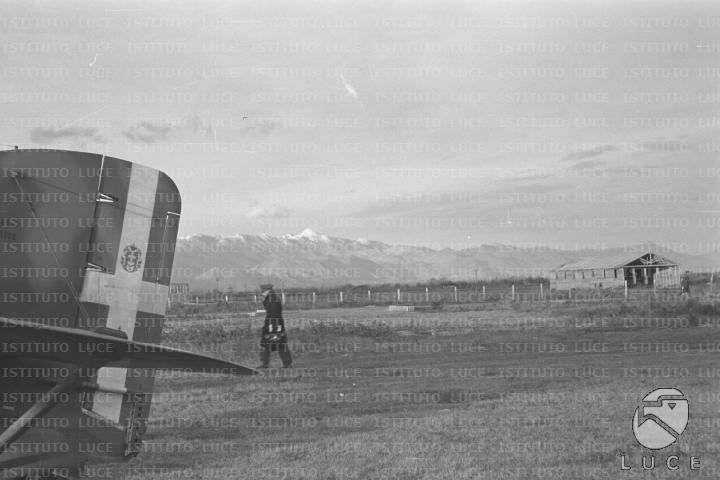 Veduta di un campo di aviazione con hangar e montagne sullo sfondo ... Veduta di un campo di aviazione con hangar e montagne sullo sfondo ...